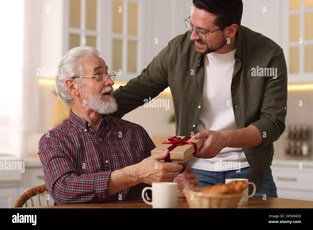 Son giving gift box to his dad at home Stock Photo - Alamy