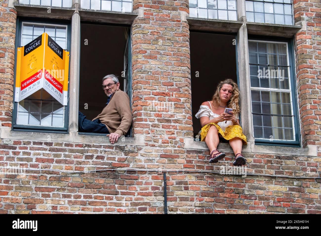 On lookers sit in widows during the Catholic festival of the Procession ...