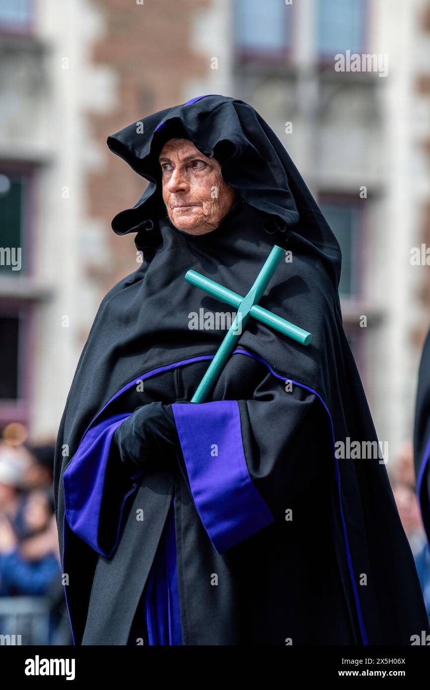 A woman dressed in traditional dress carries a cross during the ...