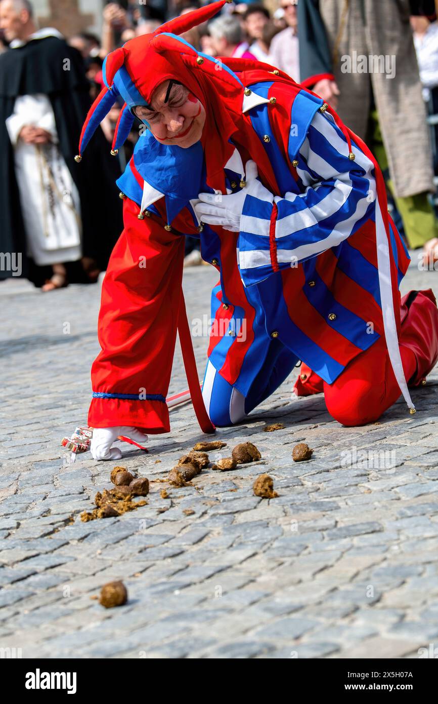 A man dressed as a jester sniffs house manure during the Catholic ...