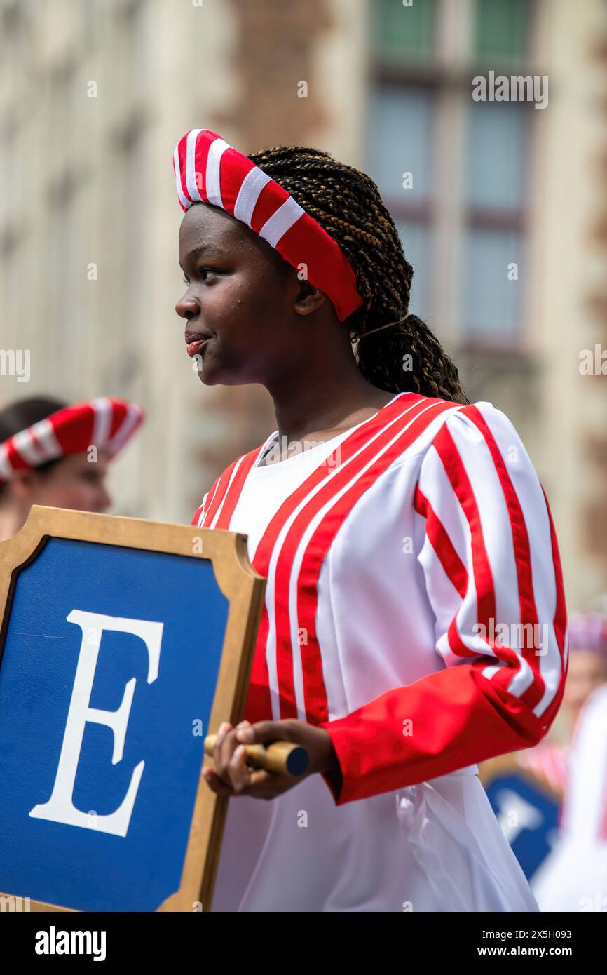 A girl in traditional dress carries part of a sign during the Catholic ...