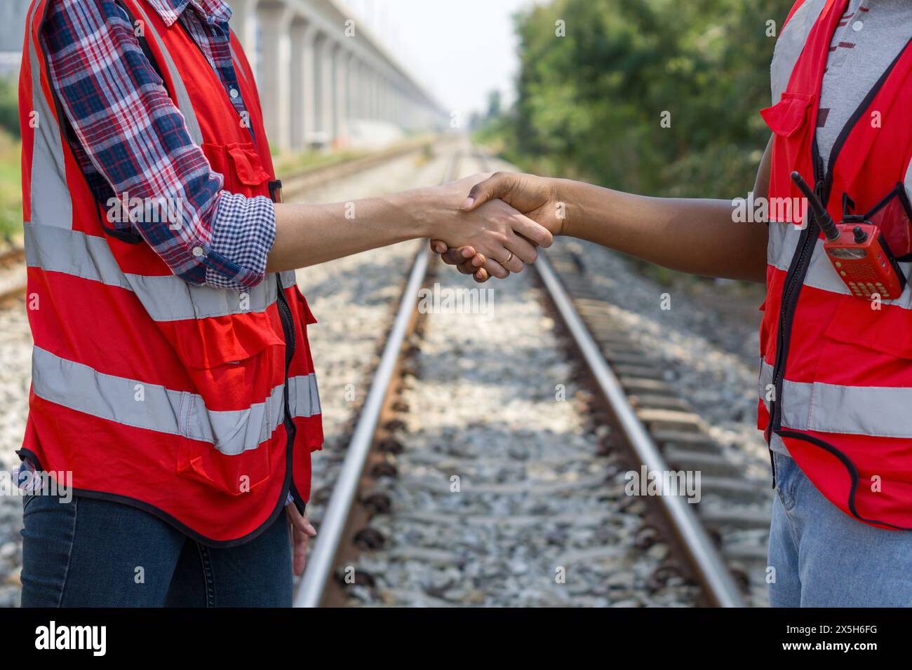 Two rail transportation engineer in reflective vest are shaking hands ...