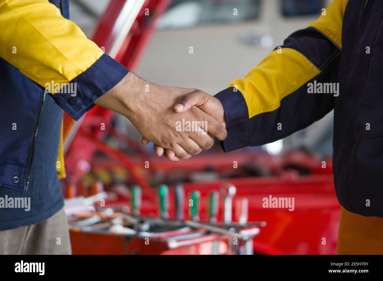 Two mechanic in work uniform engaged in a handshake. Atmosphere in ...