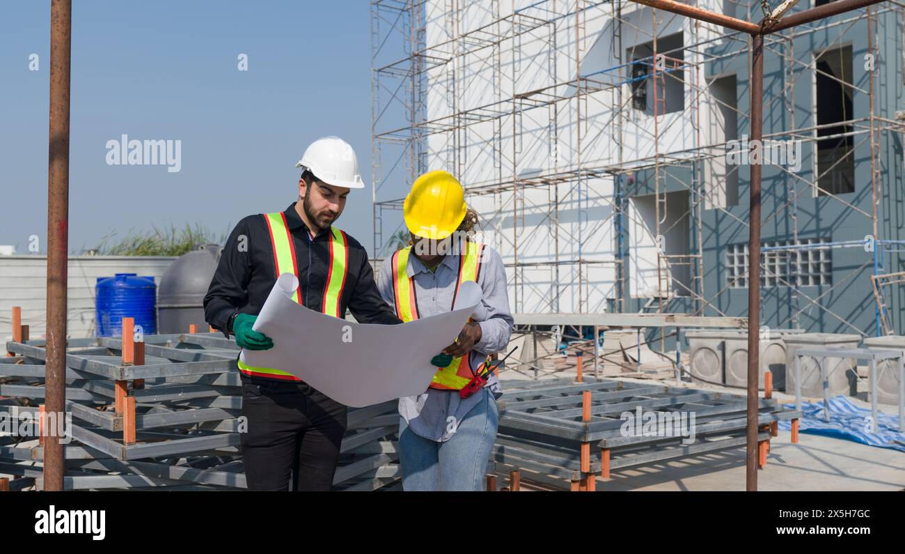Two construction worker looking at a floor plan, standing in front of a ...