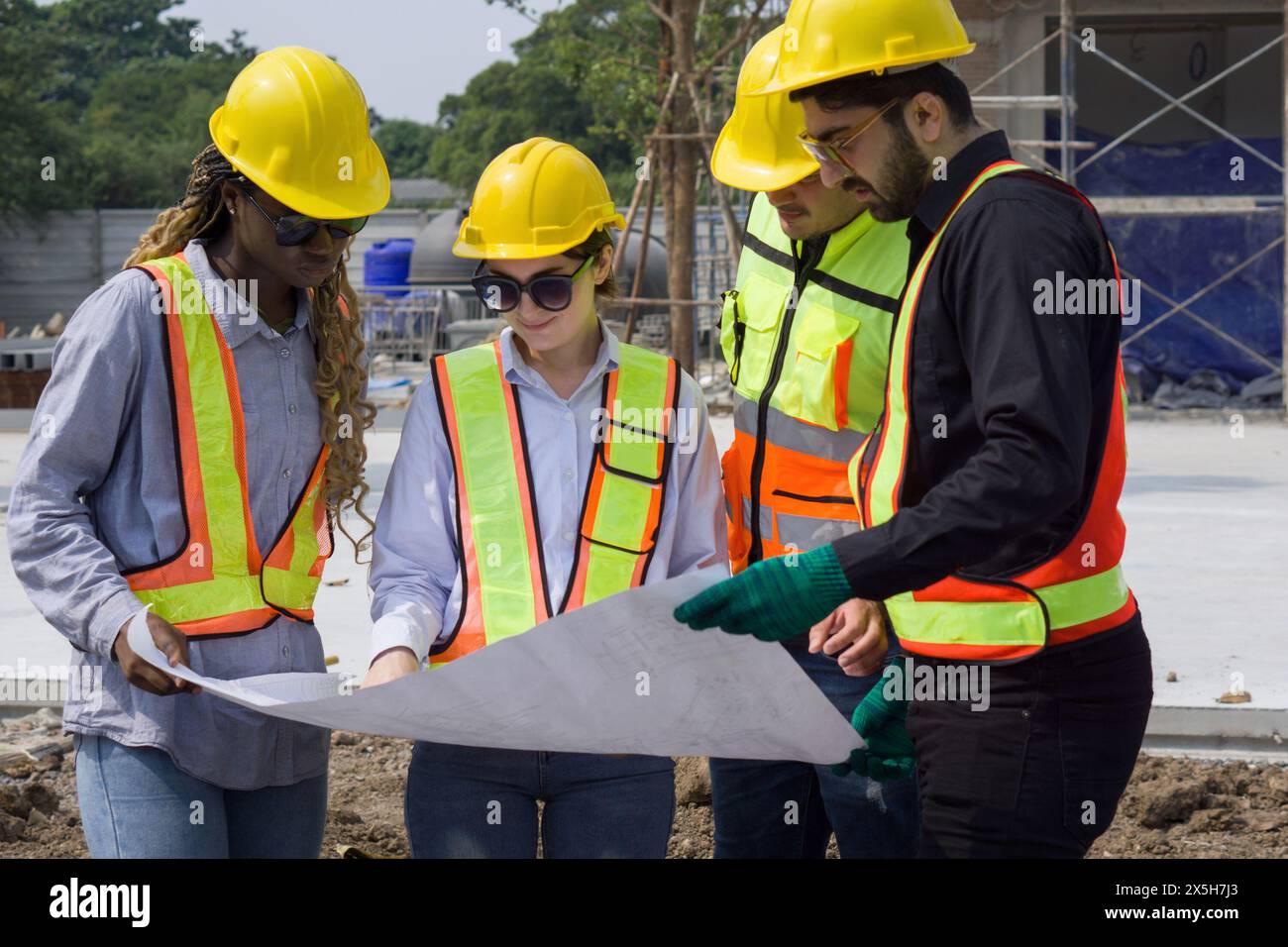 Group of construction workers gathered at a construction site reviewing ...