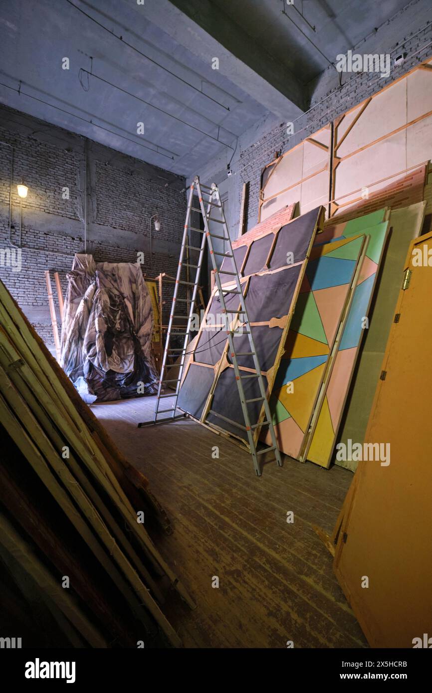 A tall ladder and various set piece flats in a storage, loading dock ...