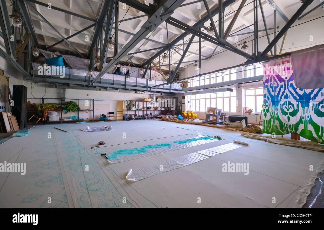 A large backdrop is being painted in a backstage work room. At the ...