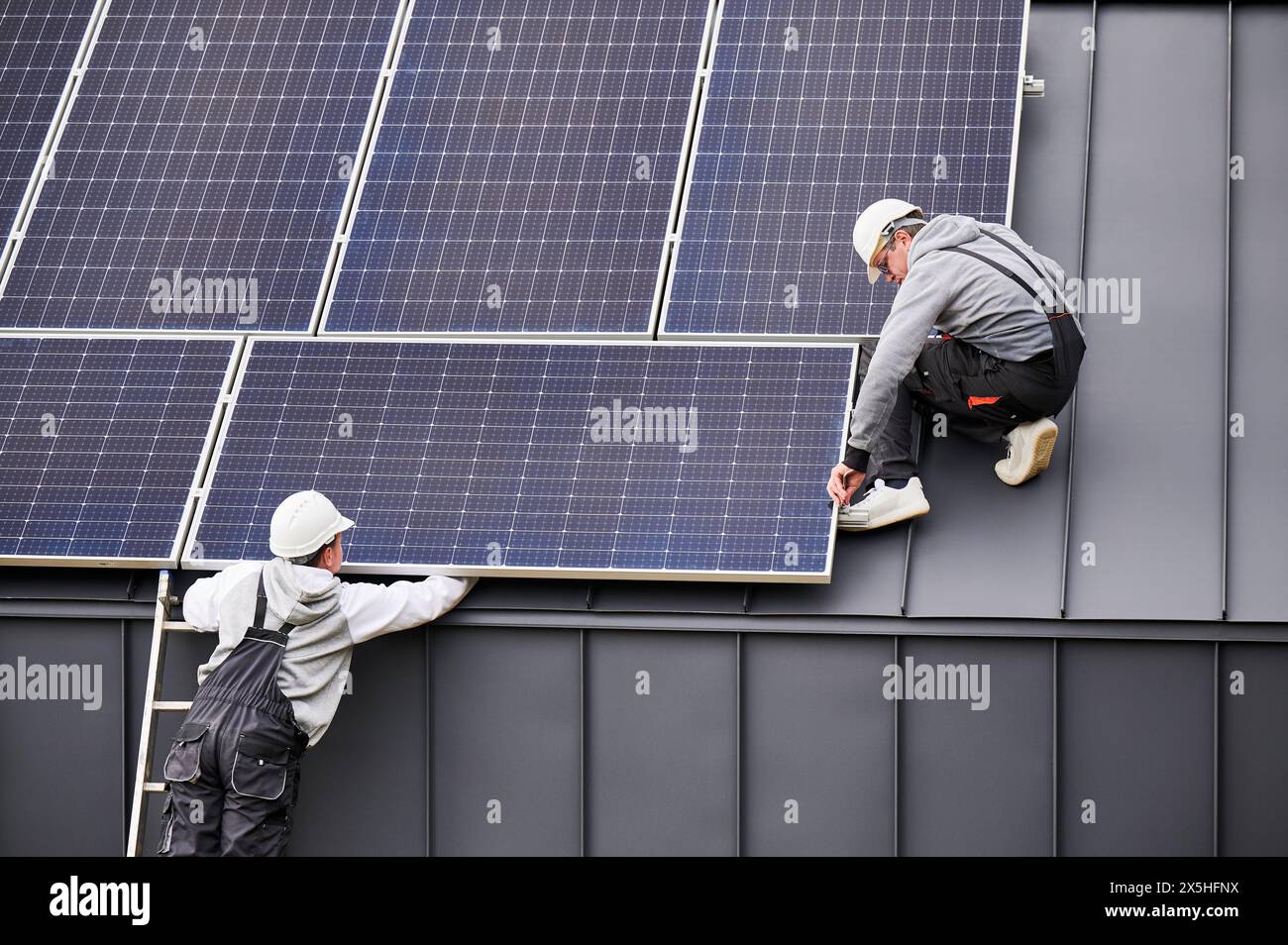Technicians connecting cables while installing photovoltaic solar ...