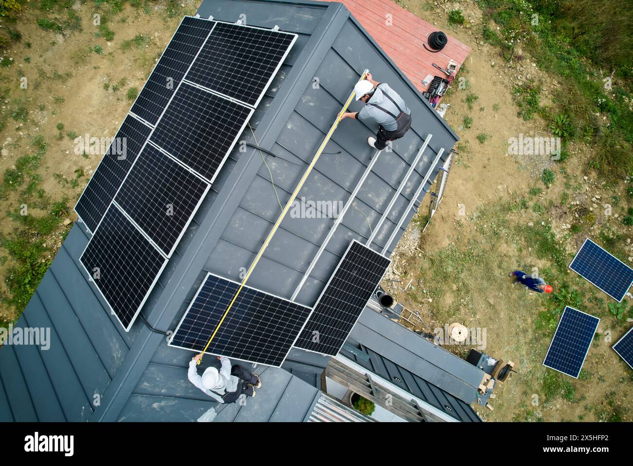 Builders measuring solar panels with tape measure. Aerial view of ...