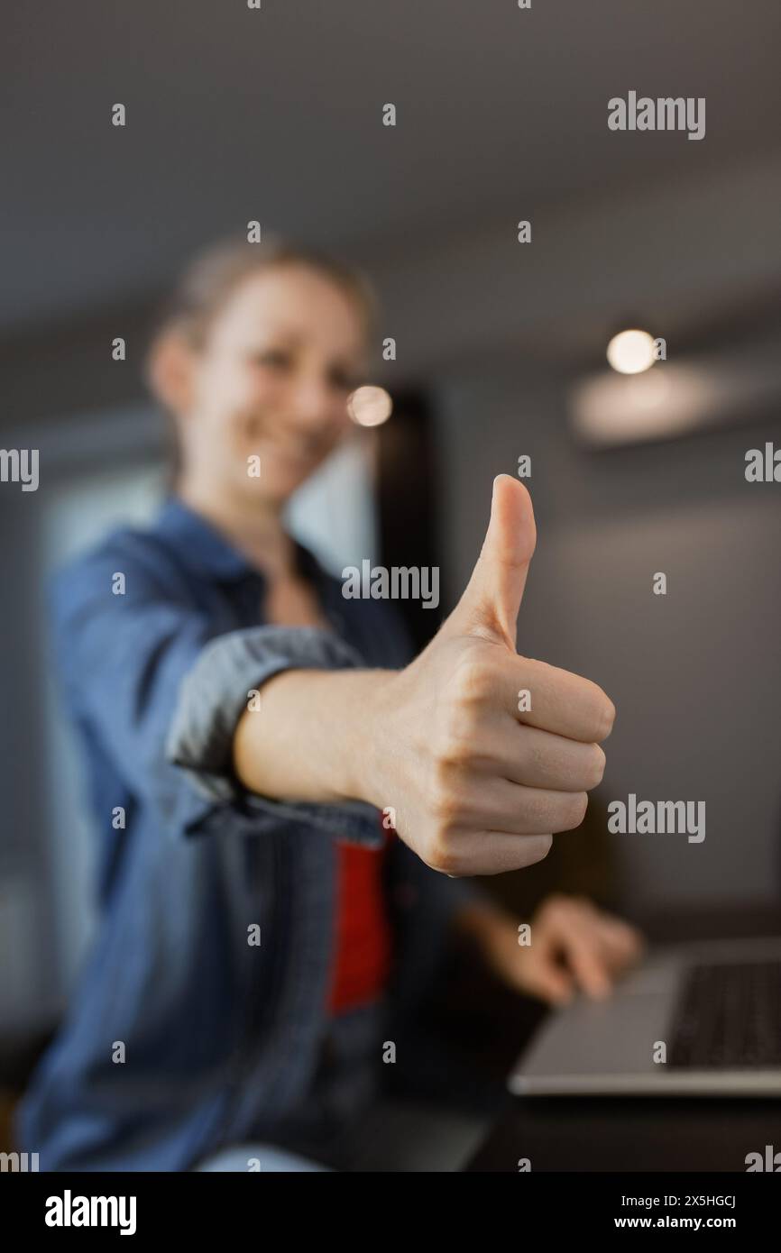 A positive young professional woman with a smile gestures a thumbs up ...