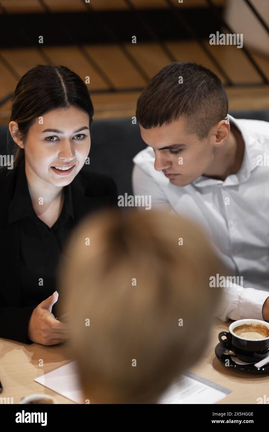 A business meeting captured from over the shoulder, showing a young man ...