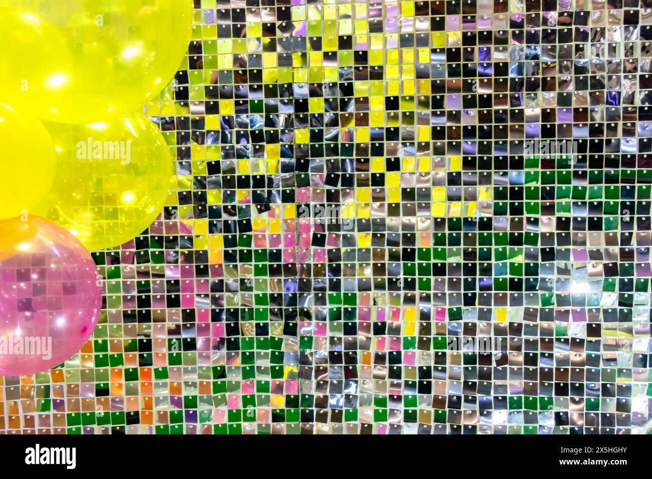 A mosaic background of silver glitter tiles with a yellow balloon ...