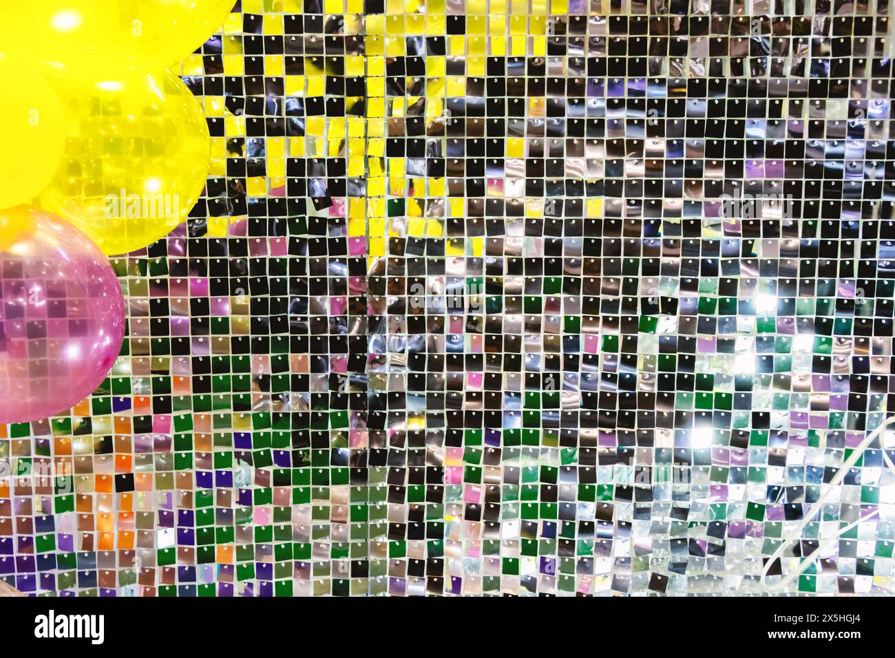 A mosaic background of silver glitter tiles with a yellow balloon ...