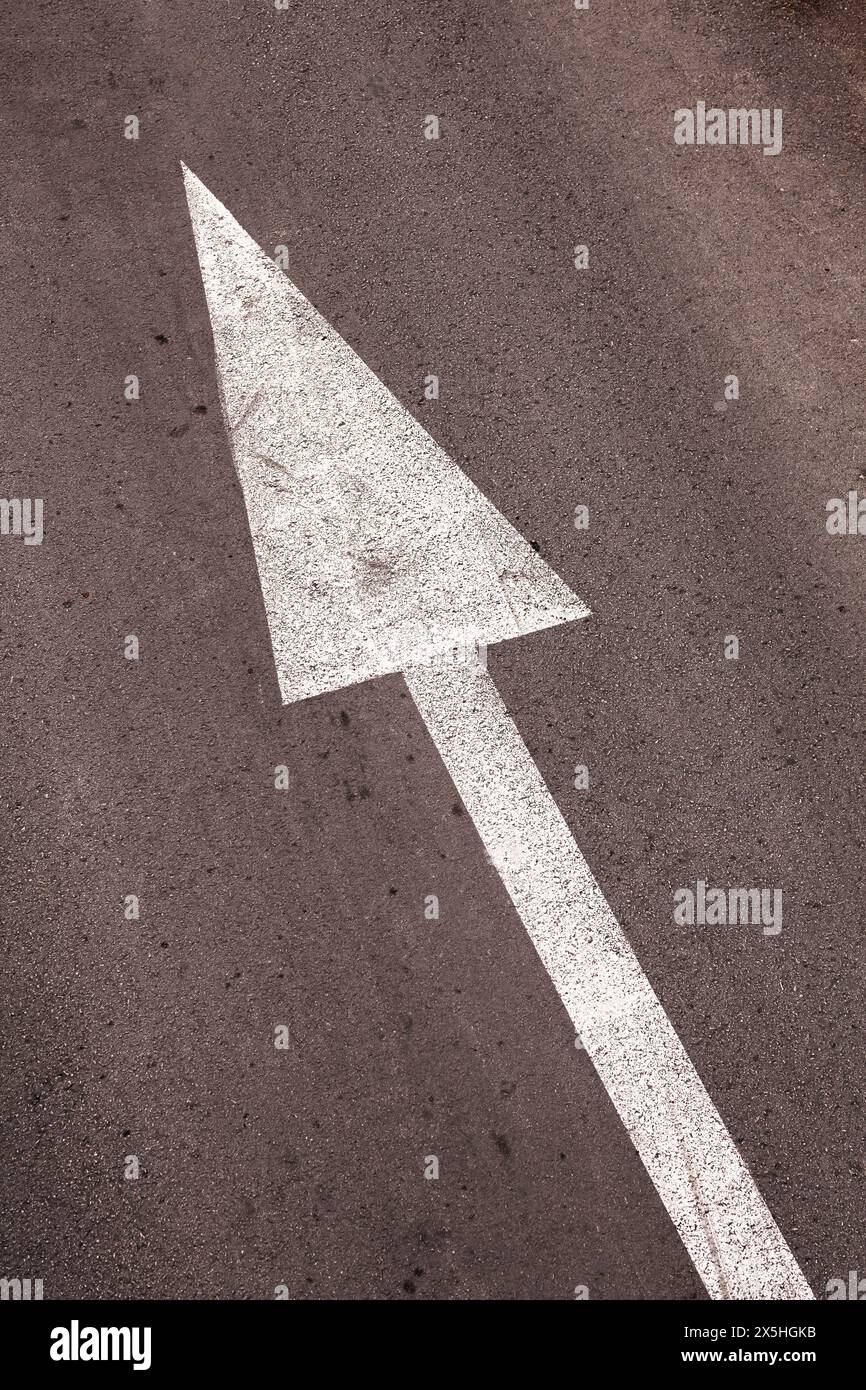 Image of a white arrow painted on an asphalt road, symbolizing ...