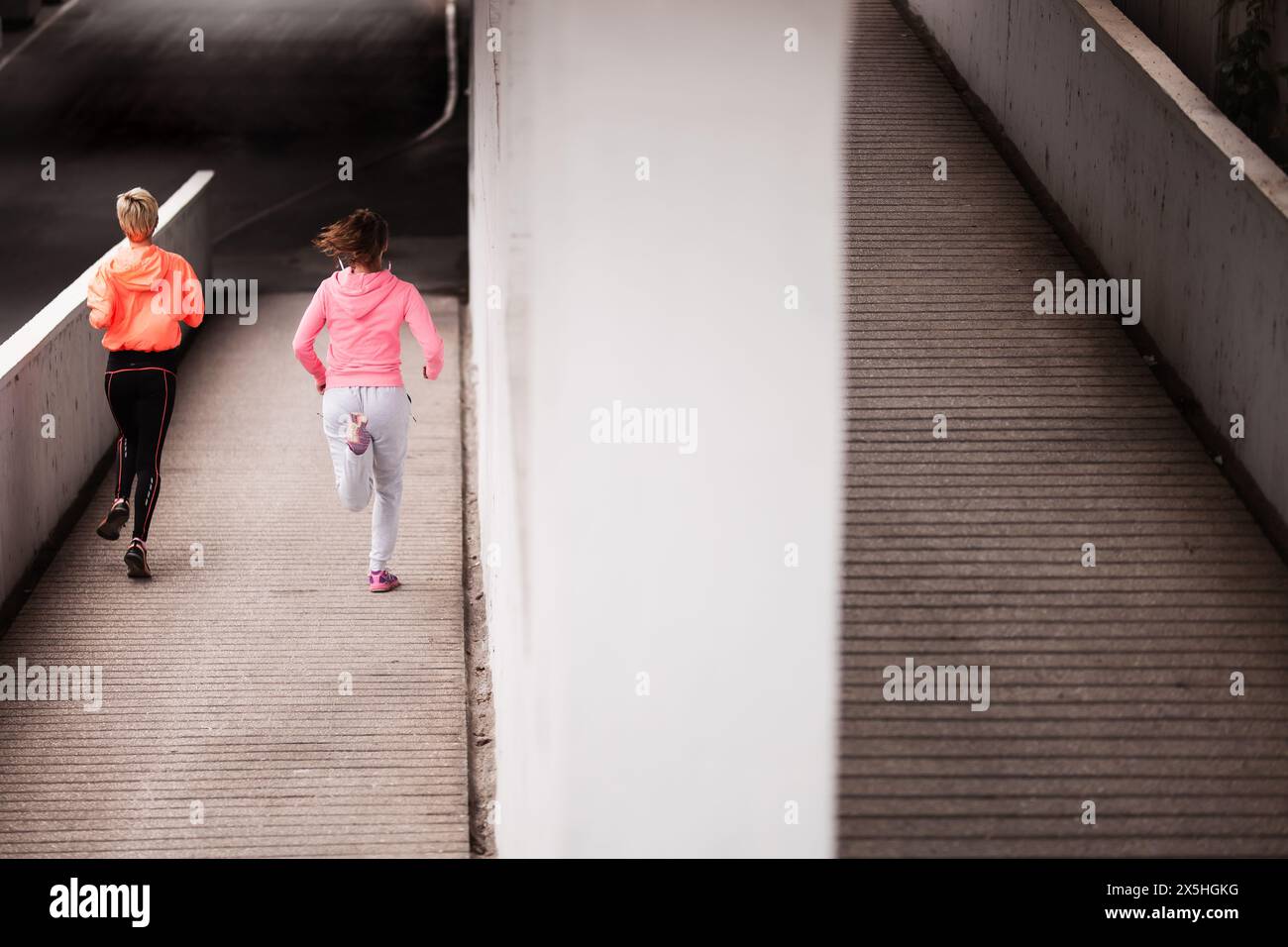 Focused on their fitness goals, two women run together on a shaded ...