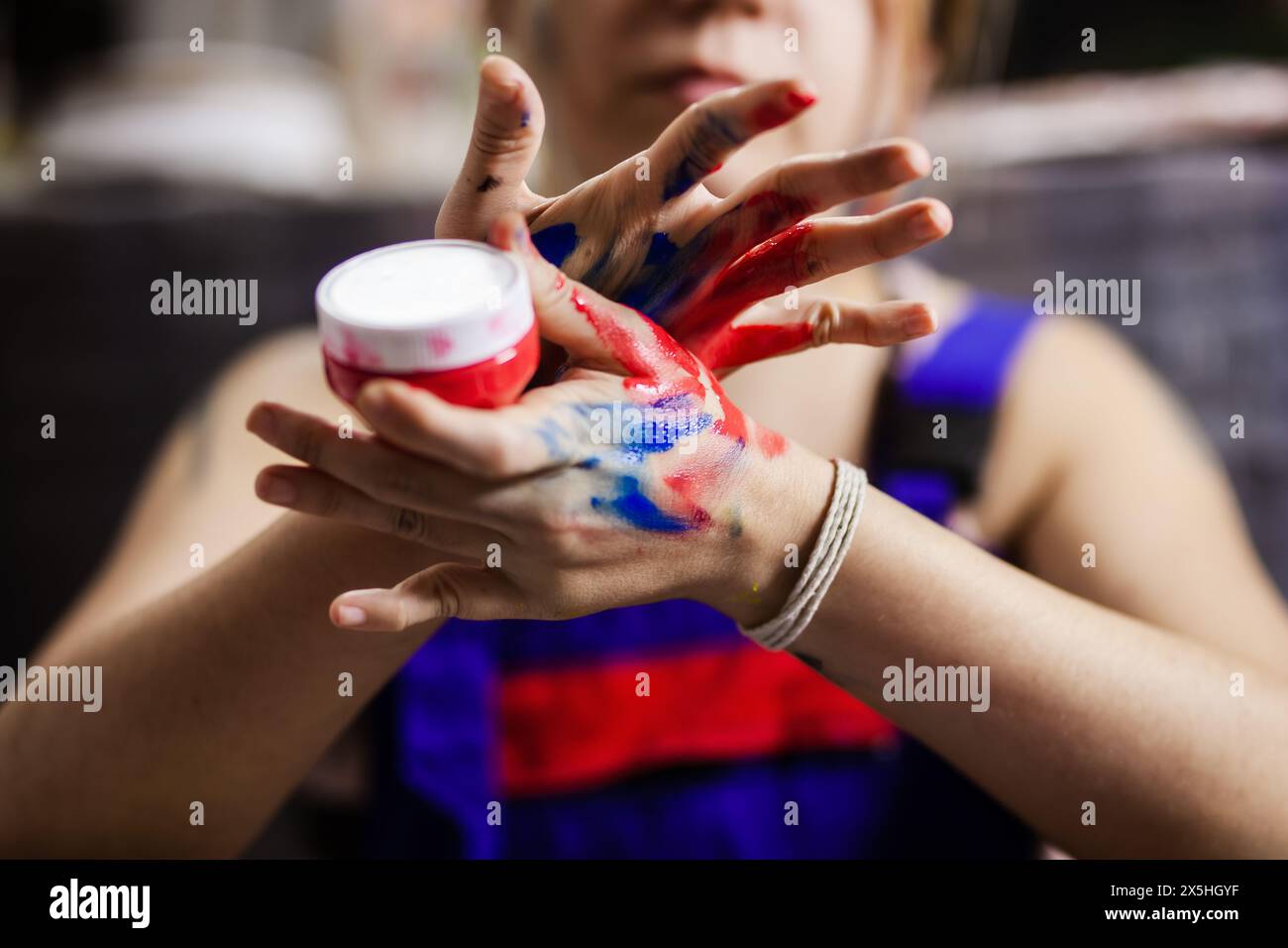 A female artist engages with her creativity, mixing vibrant red and ...