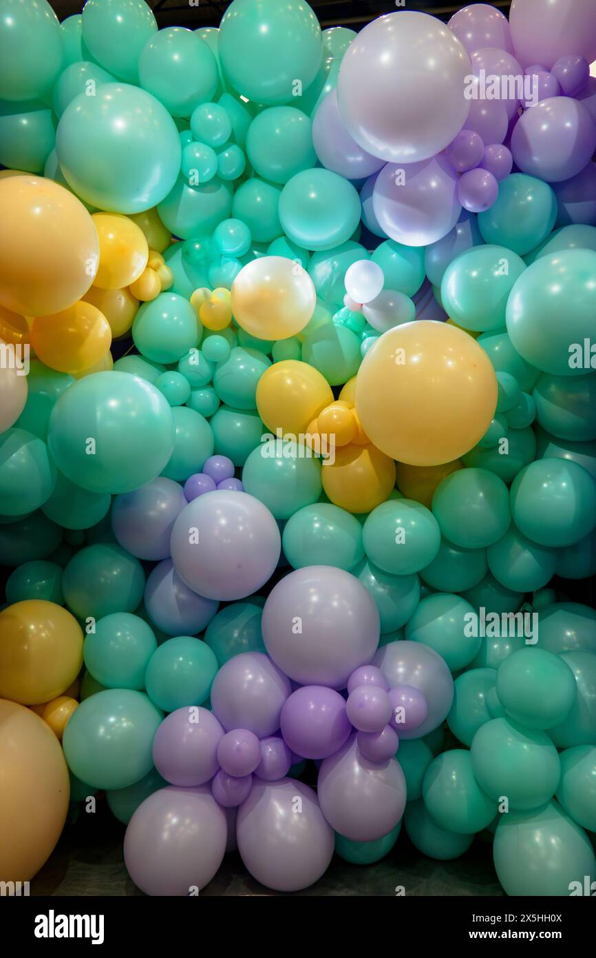 A wall hung with a lot of colorful balloons, purple, green and yellow ...