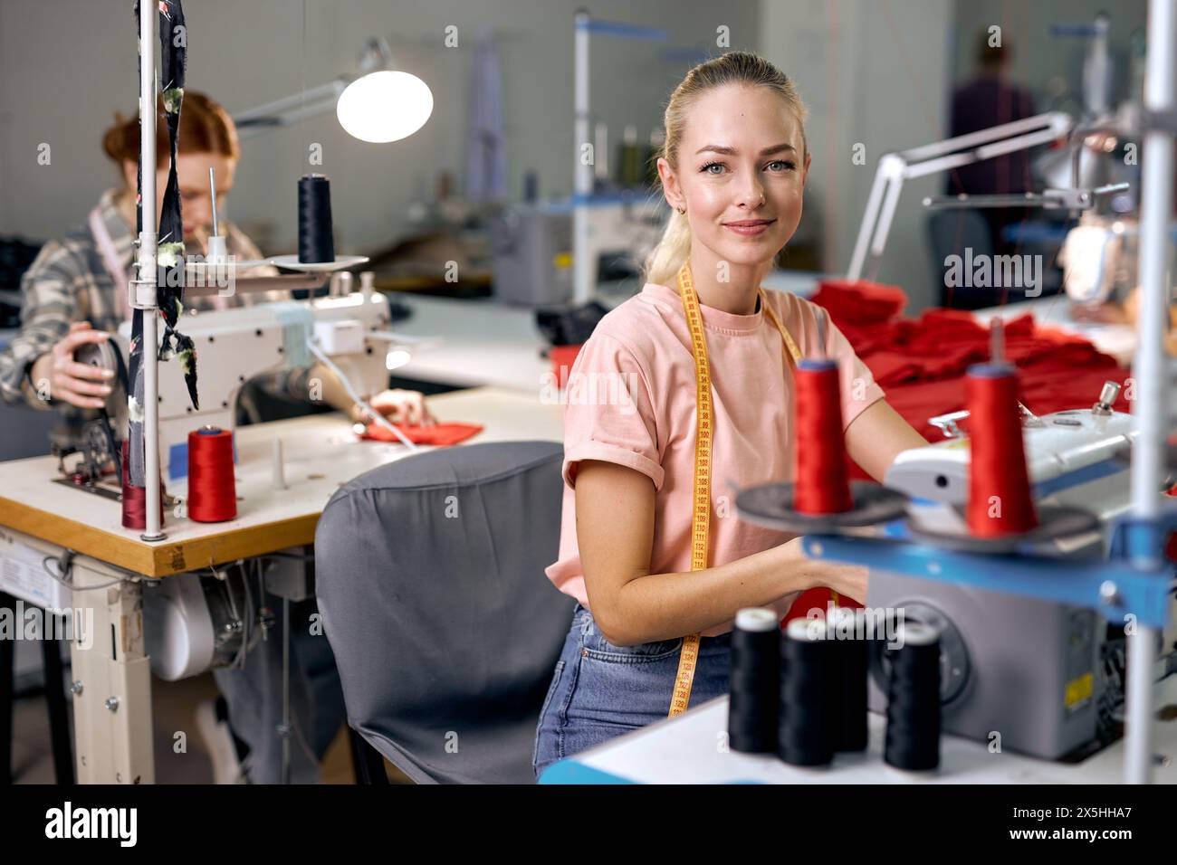 Dressmakers women sewing clothes on sewing machine in factory together ...