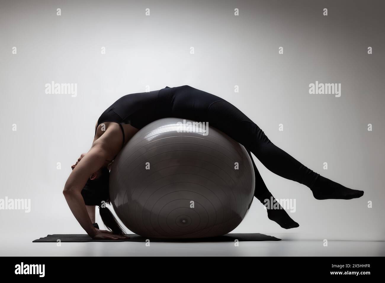 A young woman demonstrates flexibility and balance in a yoga pose on a ...