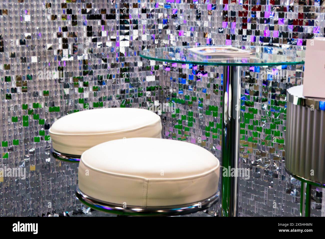 Two white bar stools and a glass tabletop on a silver shiny background ...