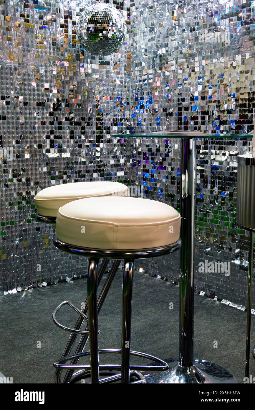 Two white bar stools and a glass tabletop on a silver shiny background ...