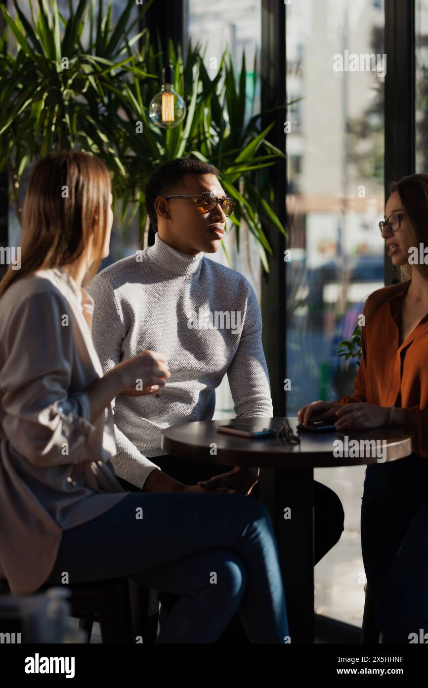 Three multiracial friends in a bar. After work party after successful ...
