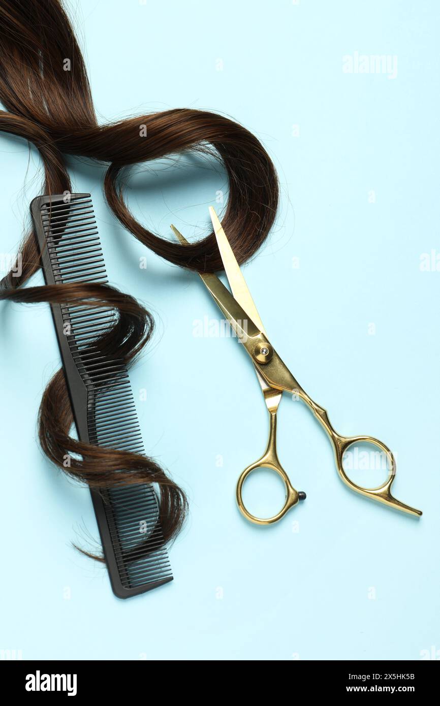 Professional hairdresser scissors and comb with brown hair strand on ...