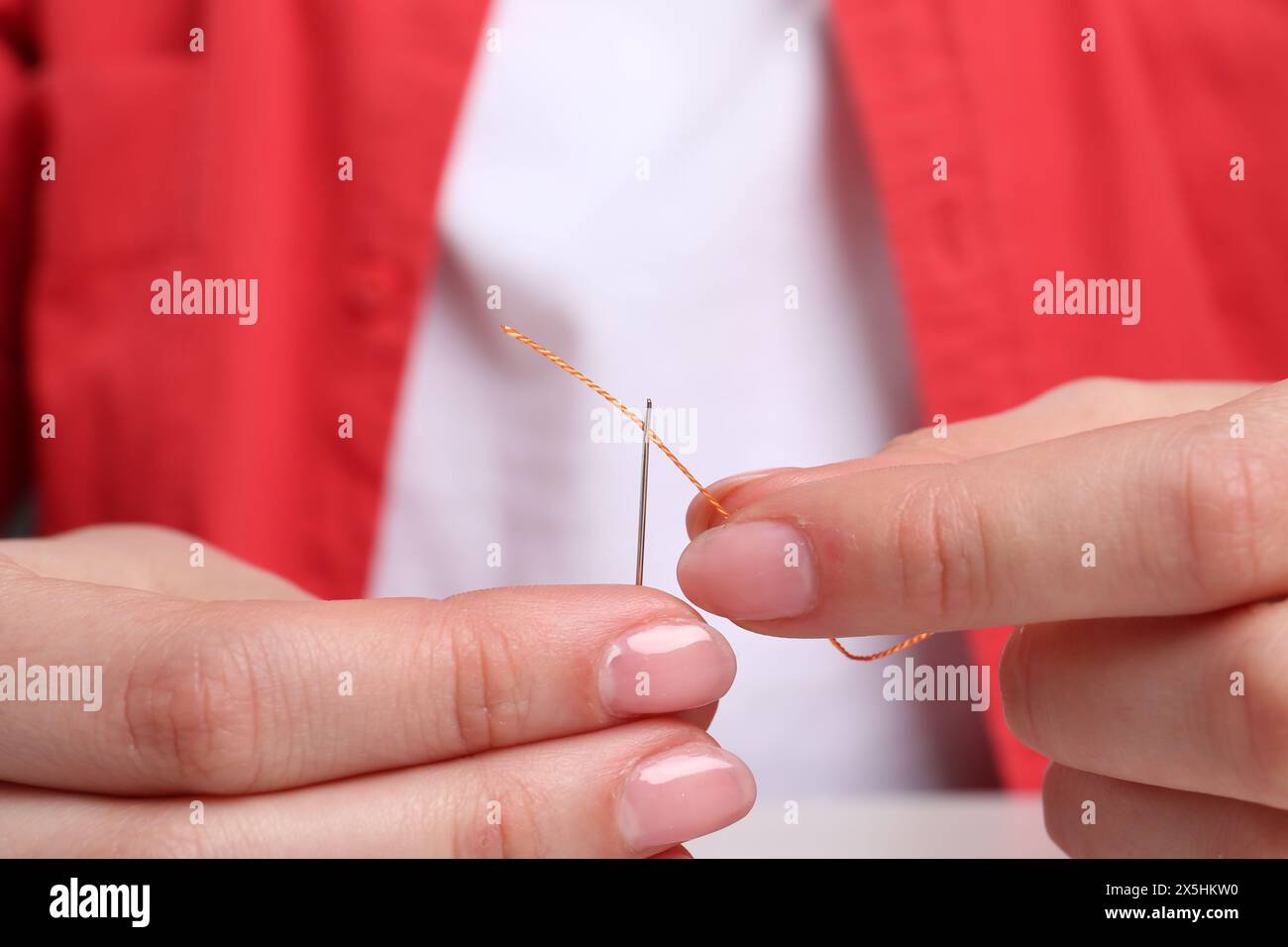 Woman inserting thread through eye of needle, closeup Stock Photo - Alamy