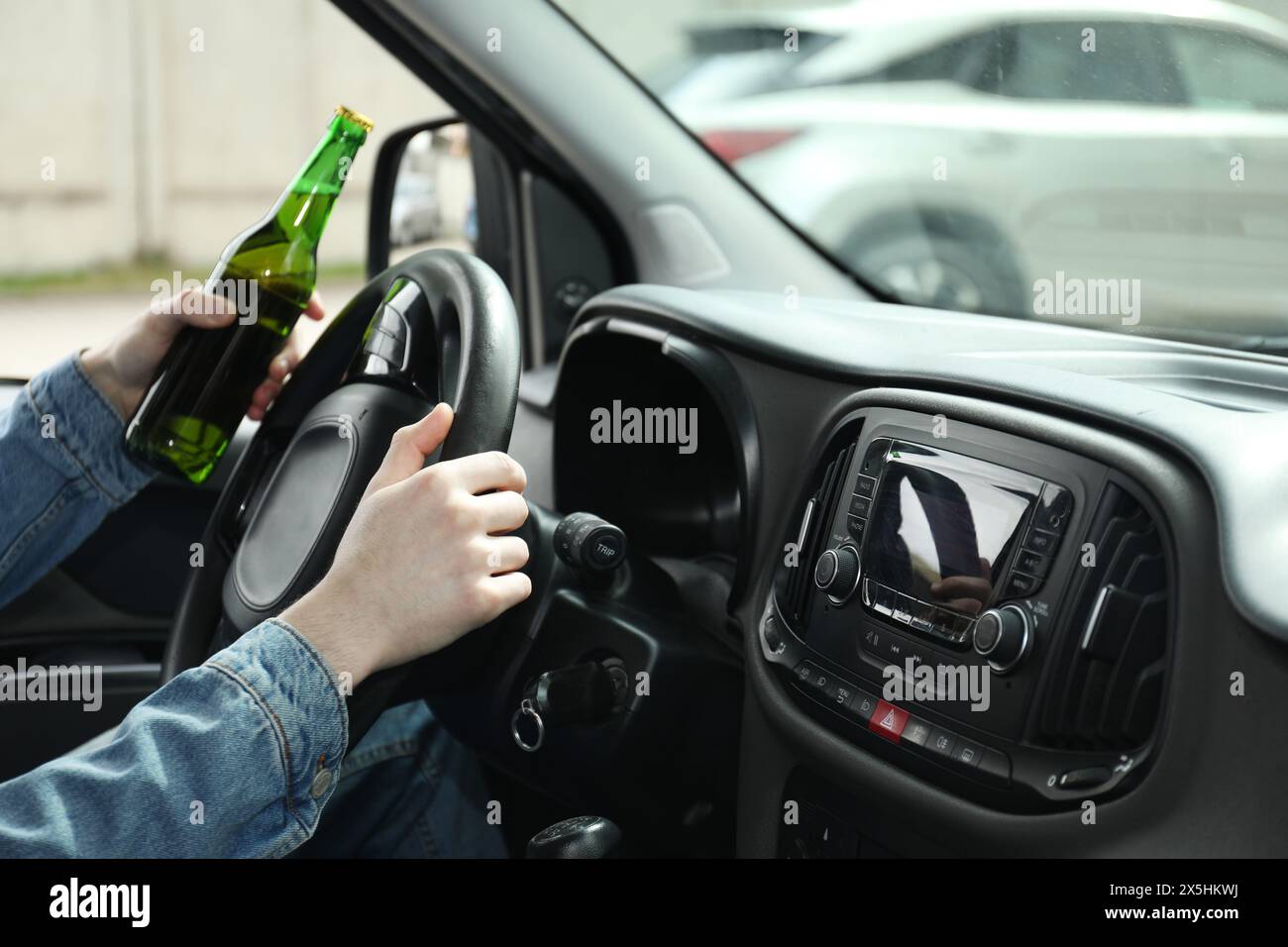 Man with bottle of beer driving car, closeup. Don't drink and drive ...