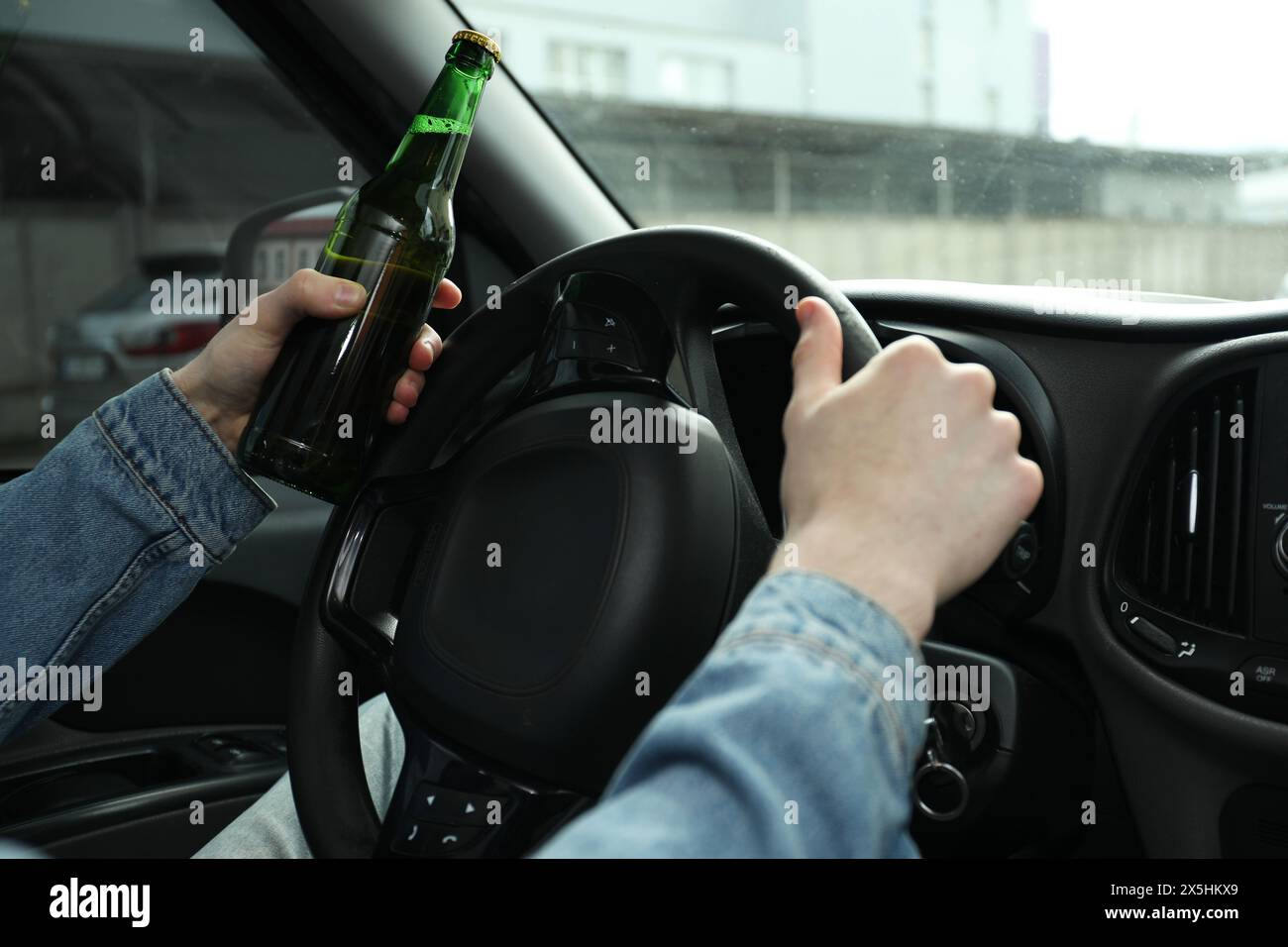 Man with bottle of beer driving car, closeup. Don't drink and drive ...