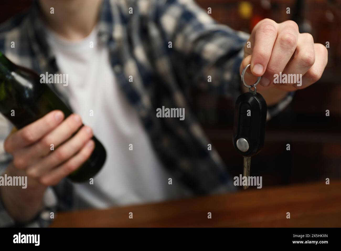 Man with bottle of beer and car keys in bar, closeup. Don't drink and ...