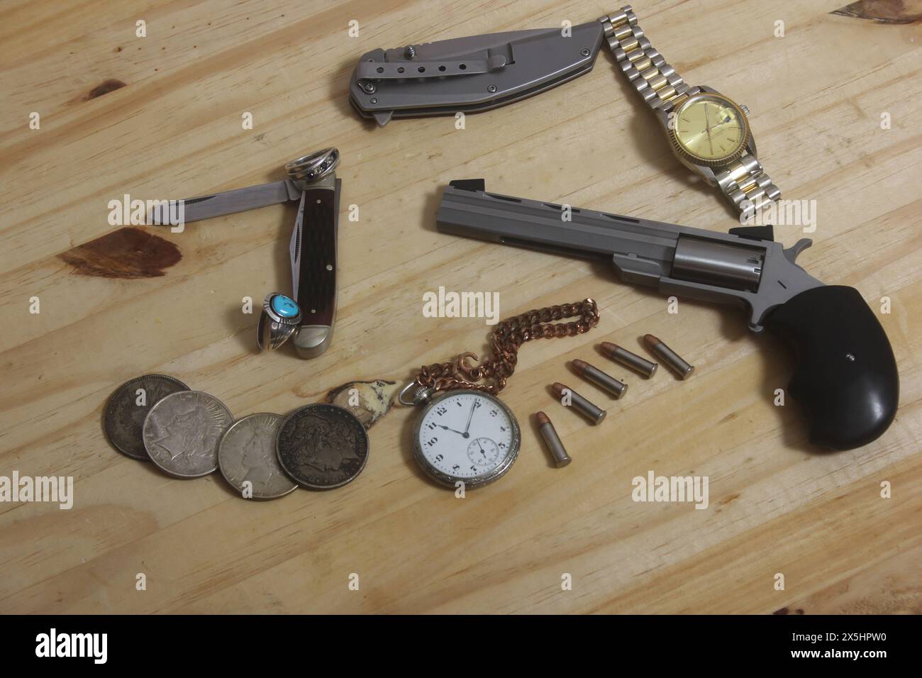 Gun and Bullets With Silver Coins and Pocket Watch on Wooden Table ...