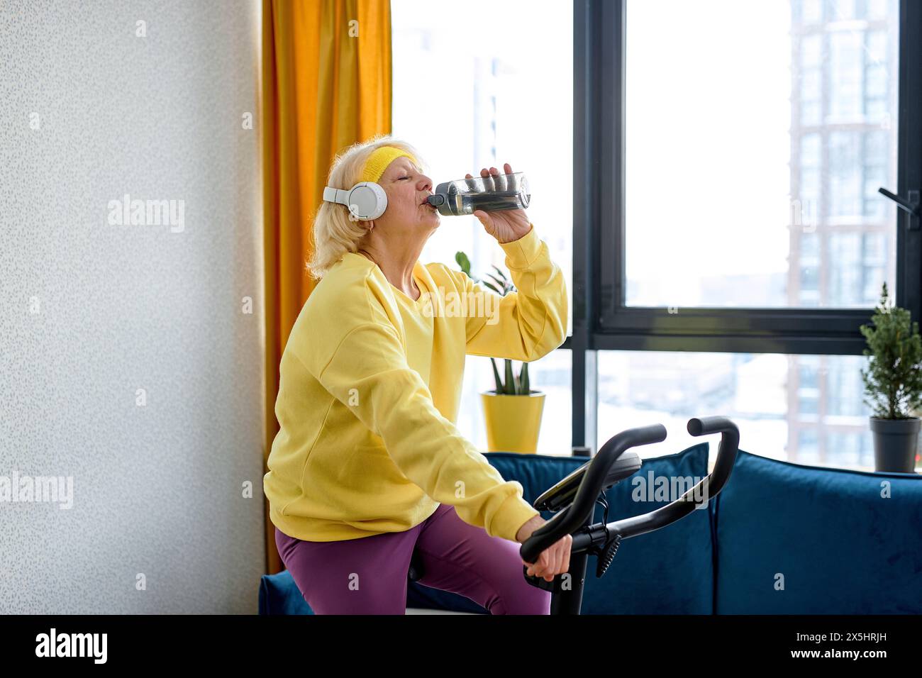 Elderly person training on stationary bicycle doing physical exercise ...