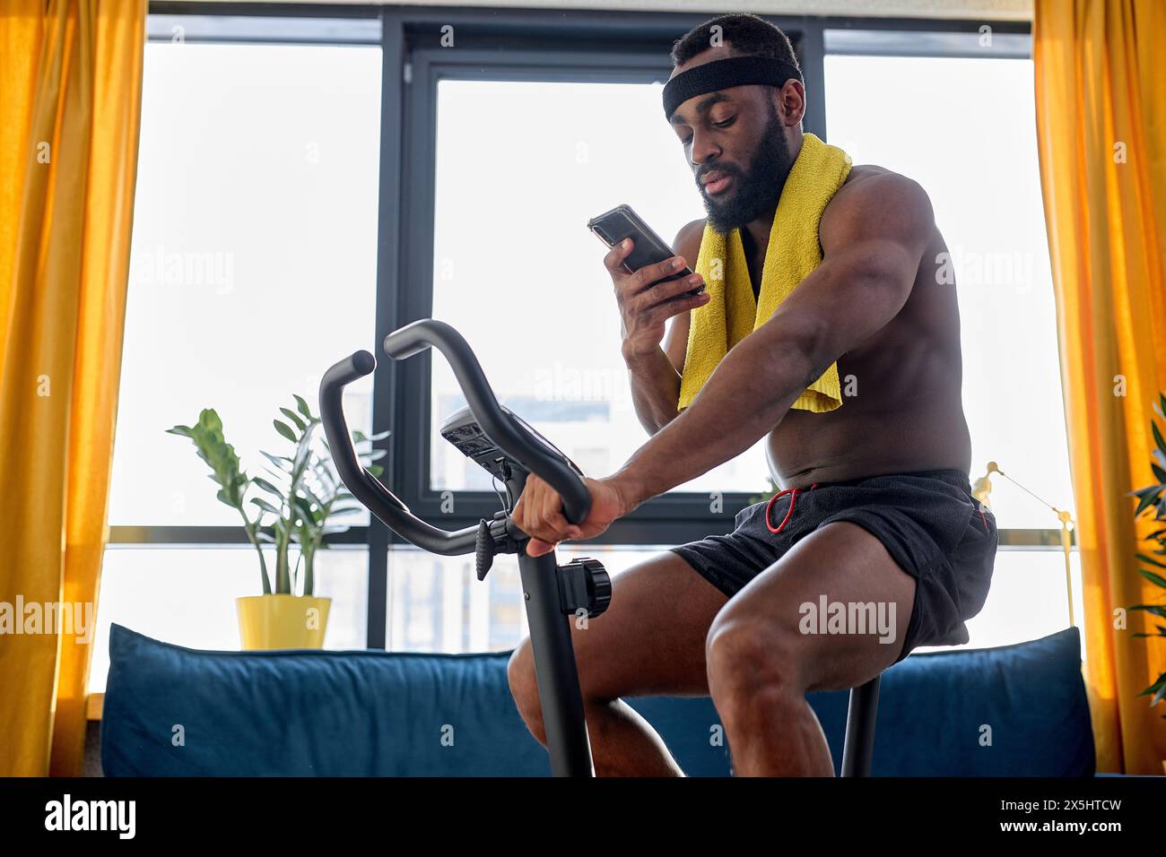Young black fitness man training on a stationary bike, exercise at home ...