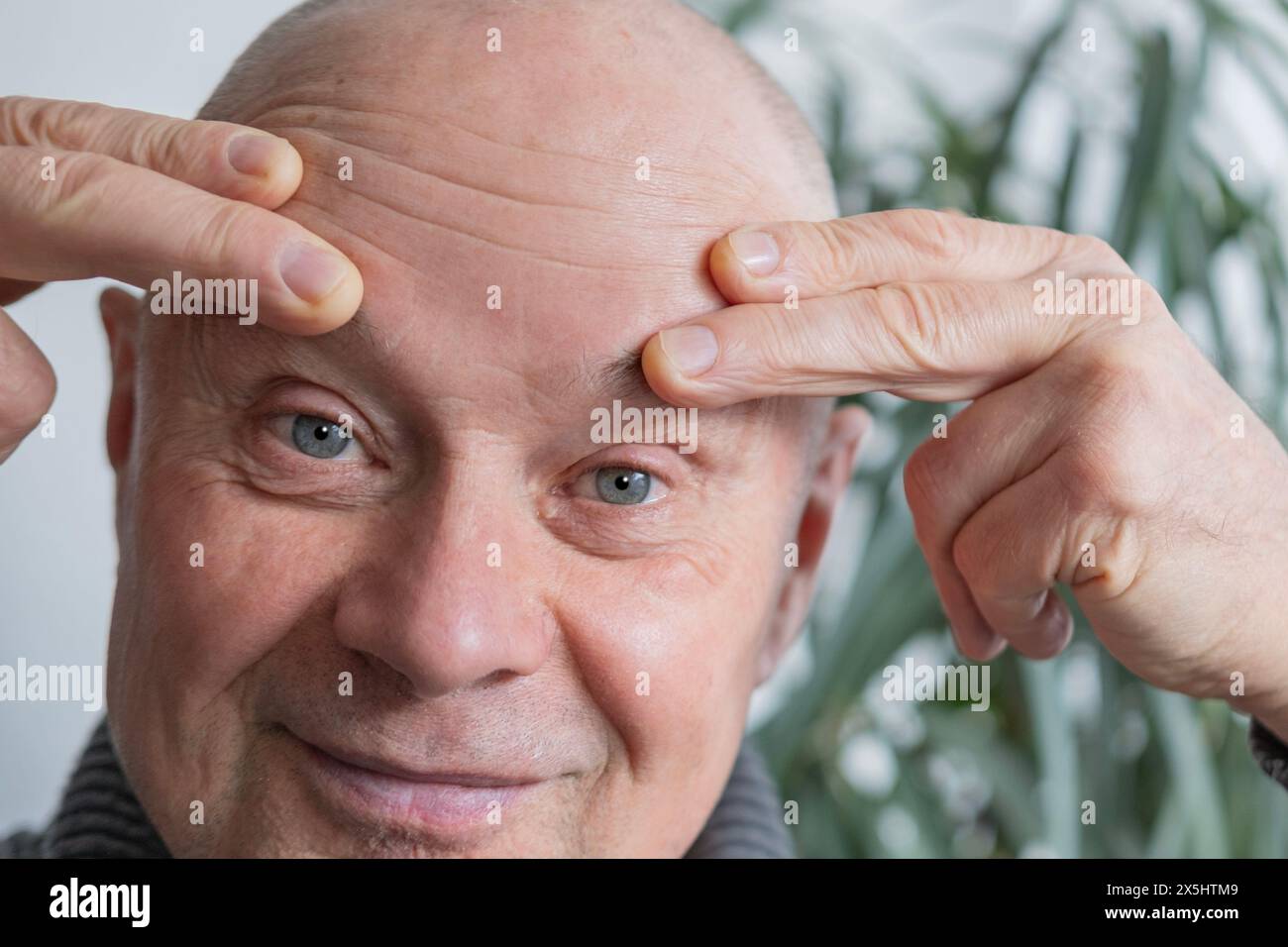 65-year-old man, senior looks carefully examines wrinkles on face, skin ...