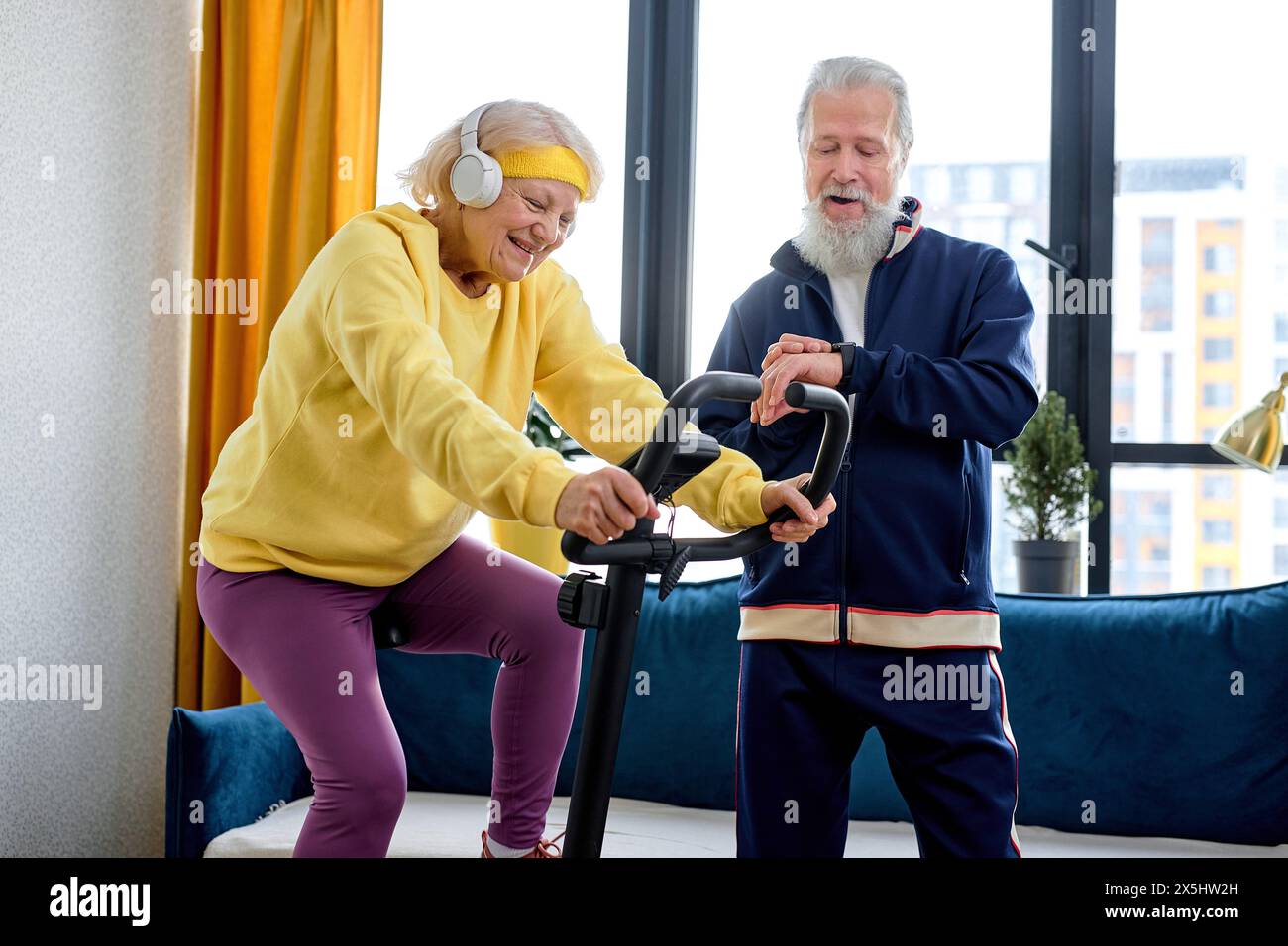 Retired lady training on stationary bicycle at home, with personal ...