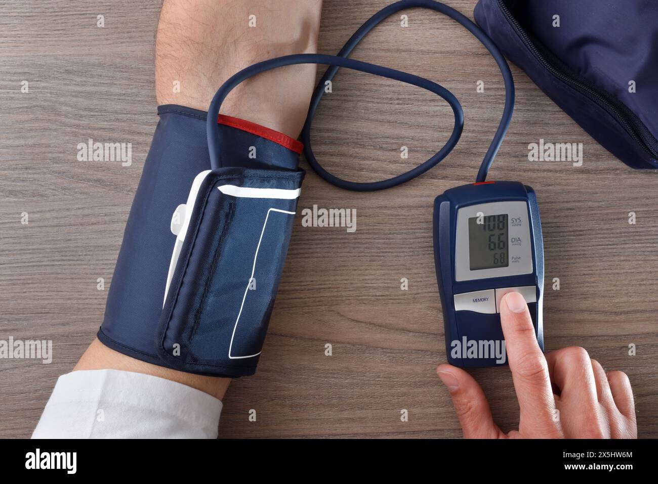 Man taking blood pressure with a digital meter on a wooden table at ...