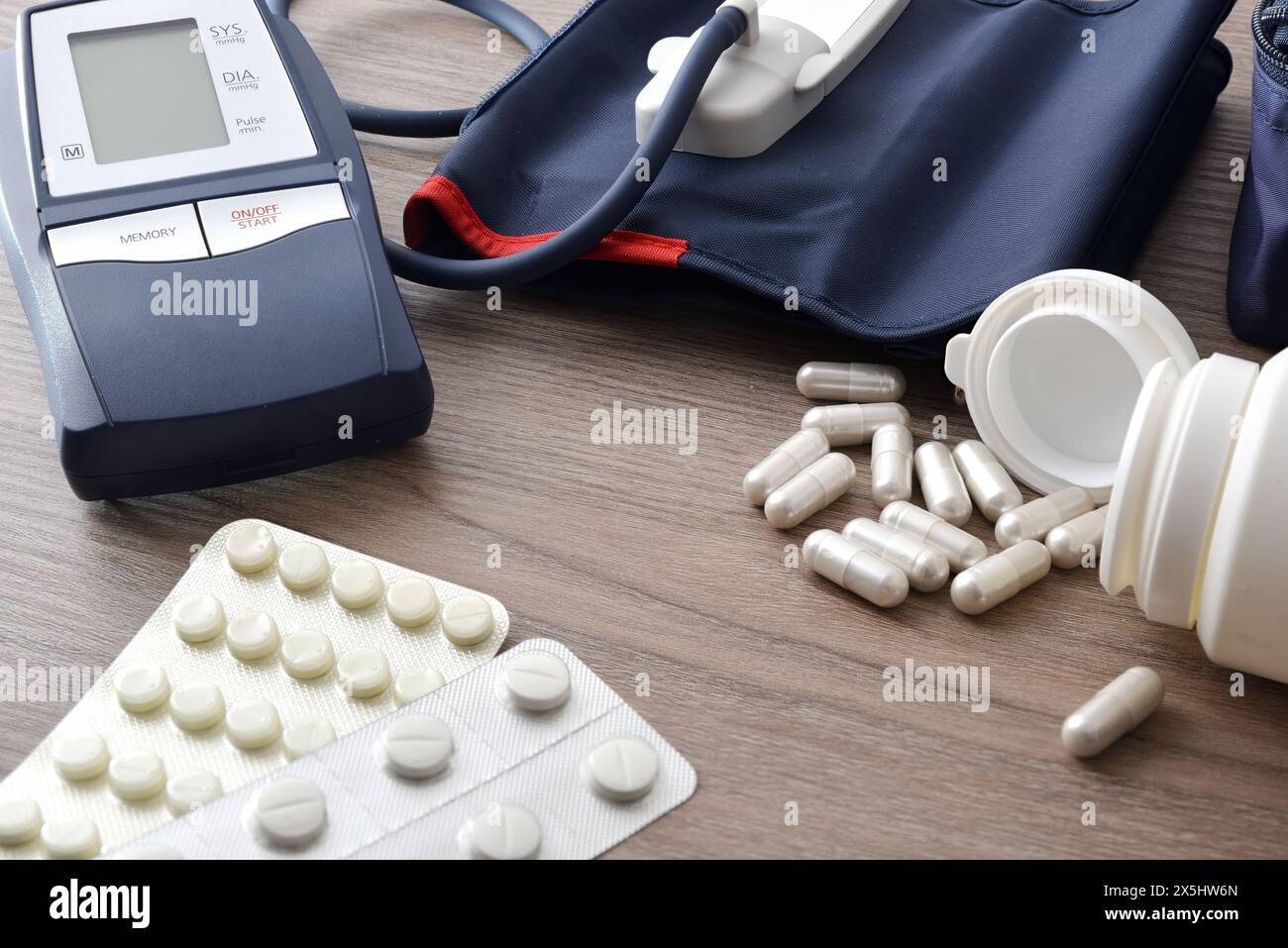 Medicines on wooden table at home with digital blood pressure monitor ...