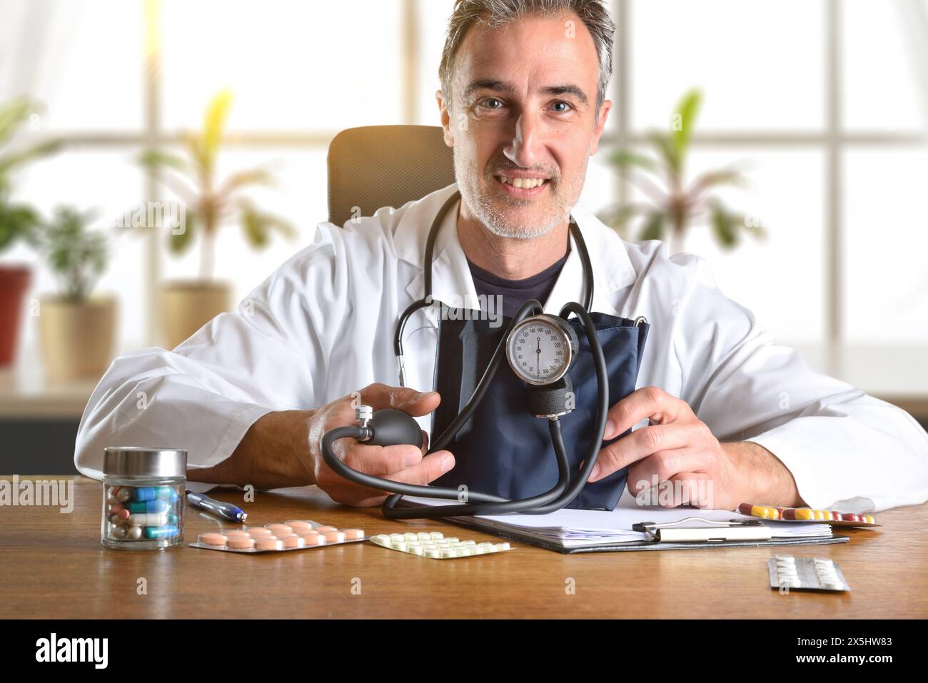 Smiling specialist doctor showing a blood pressure monitor on a ...