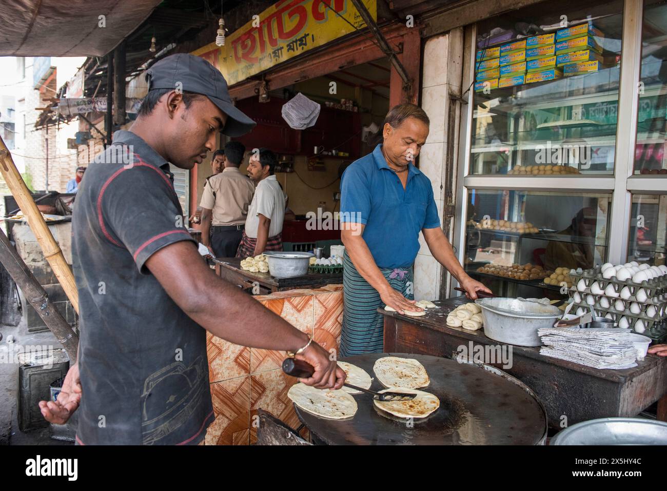 Bangladesh, Jhenaidah. A man makes chapatis in the street market to ...