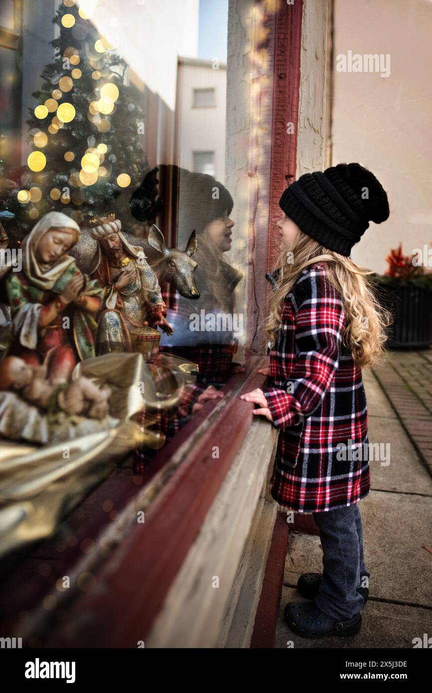 Little girl with long curls looking at nativity Stock Photo - Alamy