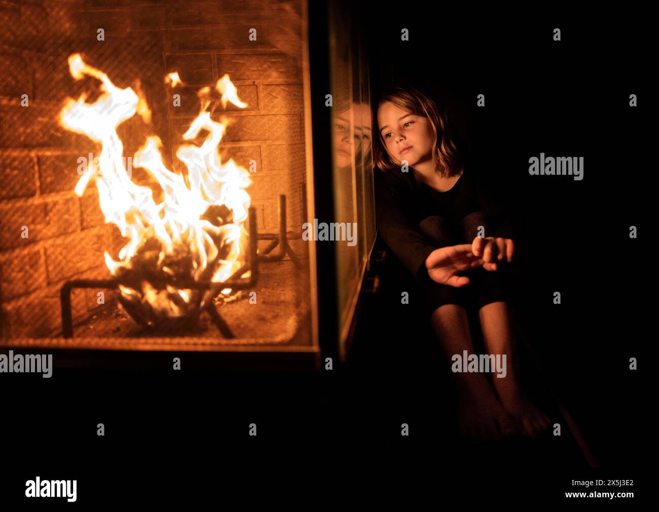 Beautiful young girl watching fireplace Stock Photo - Alamy