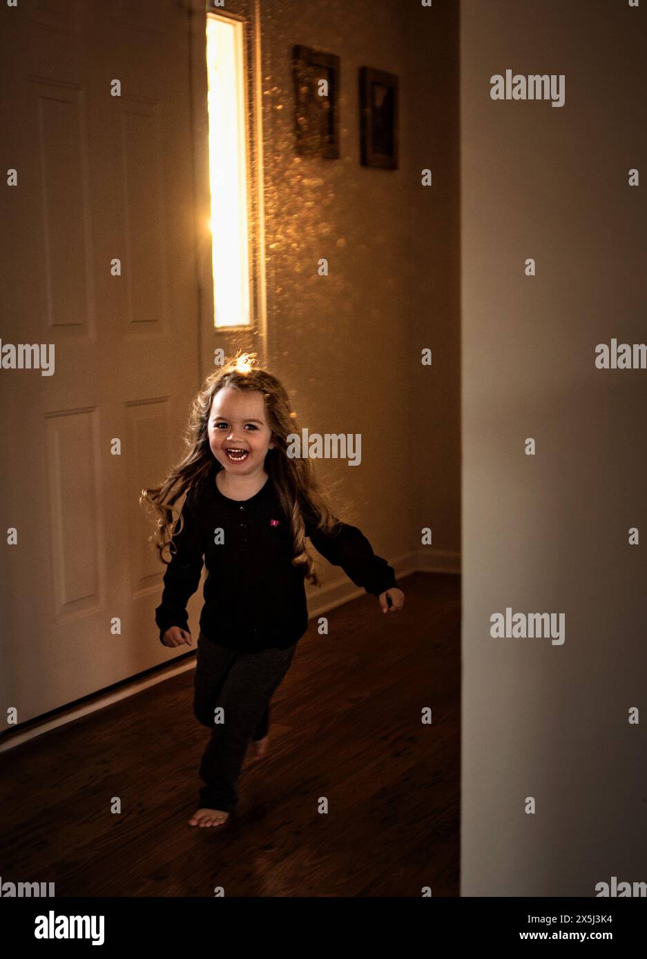 Happy little girl running through house laughing Stock Photo - Alamy