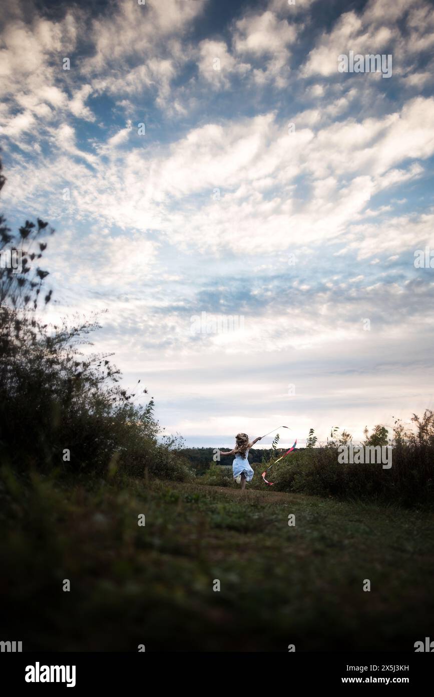 Little girl running through grassy field under blue skies Stock Photo ...