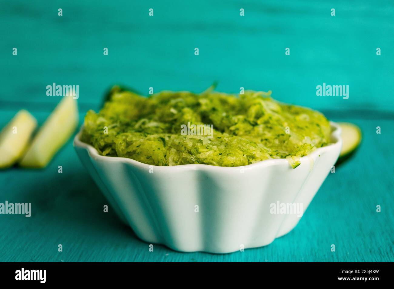 Grated zucchini mix in a white bowl, teal background! Stock Photo - Alamy
