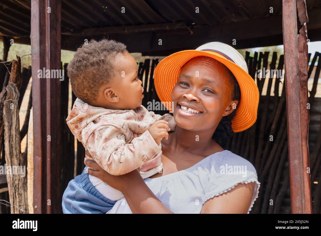 village african mother and baby standing at the entrance of the shack ...