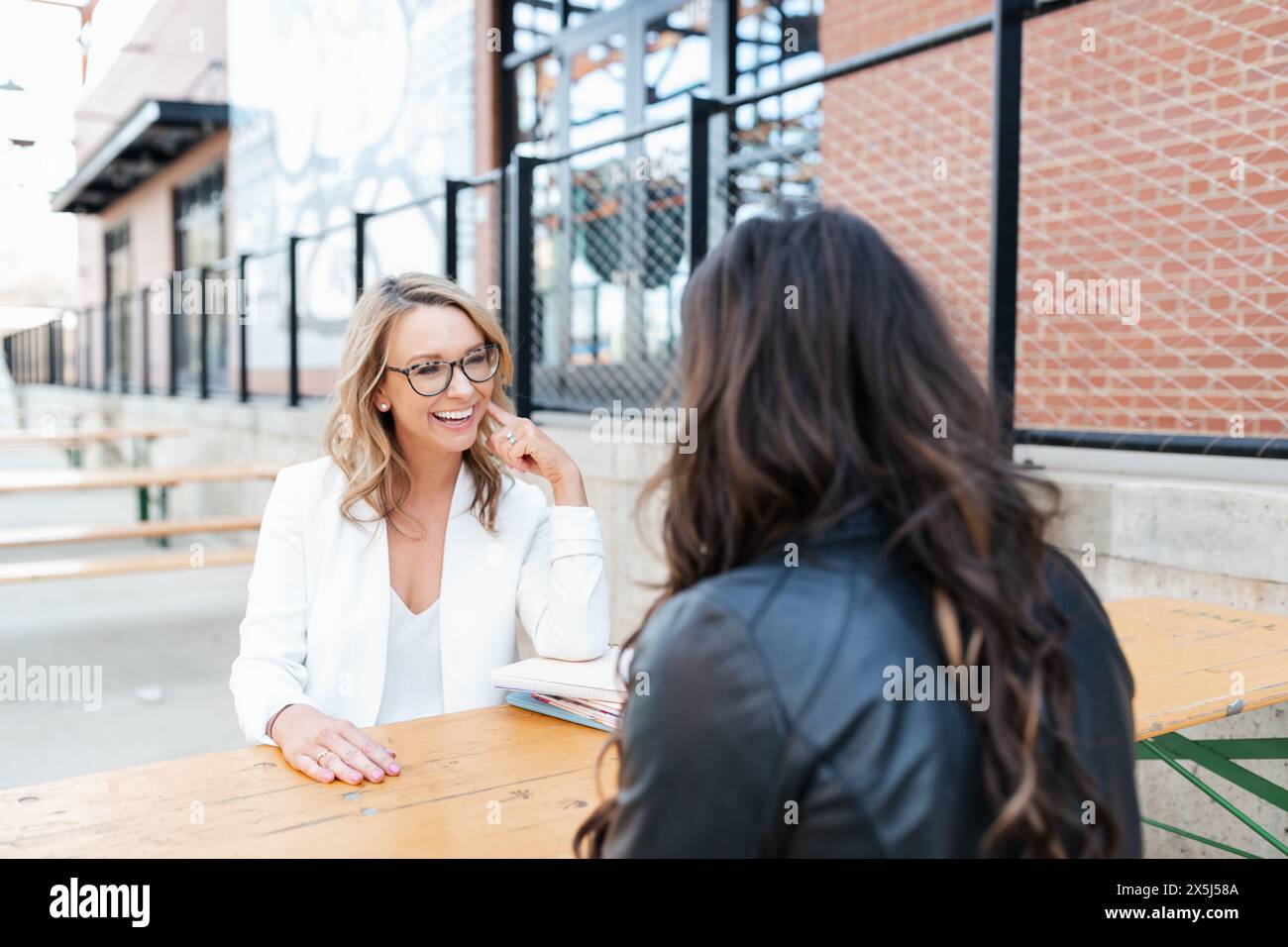 Two women talking, laughingm and wording at a table outside Stock Photo ...