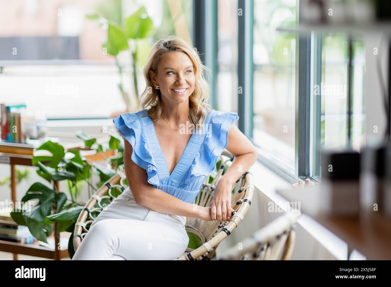 Woman smiling in coffee shop looking out window Stock Photo - Alamy