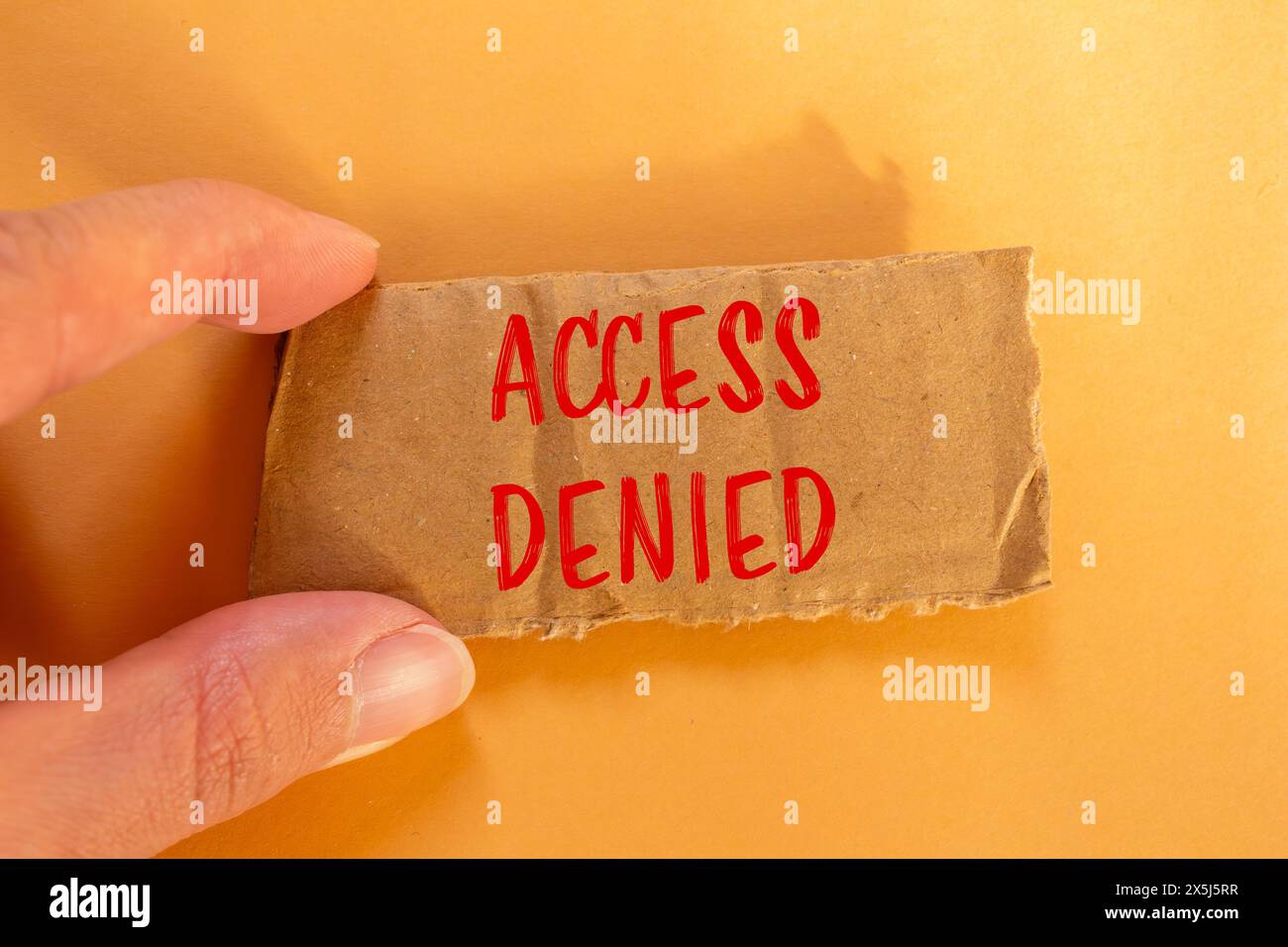 Access denied words written on ripped cardboard paper with orange ...