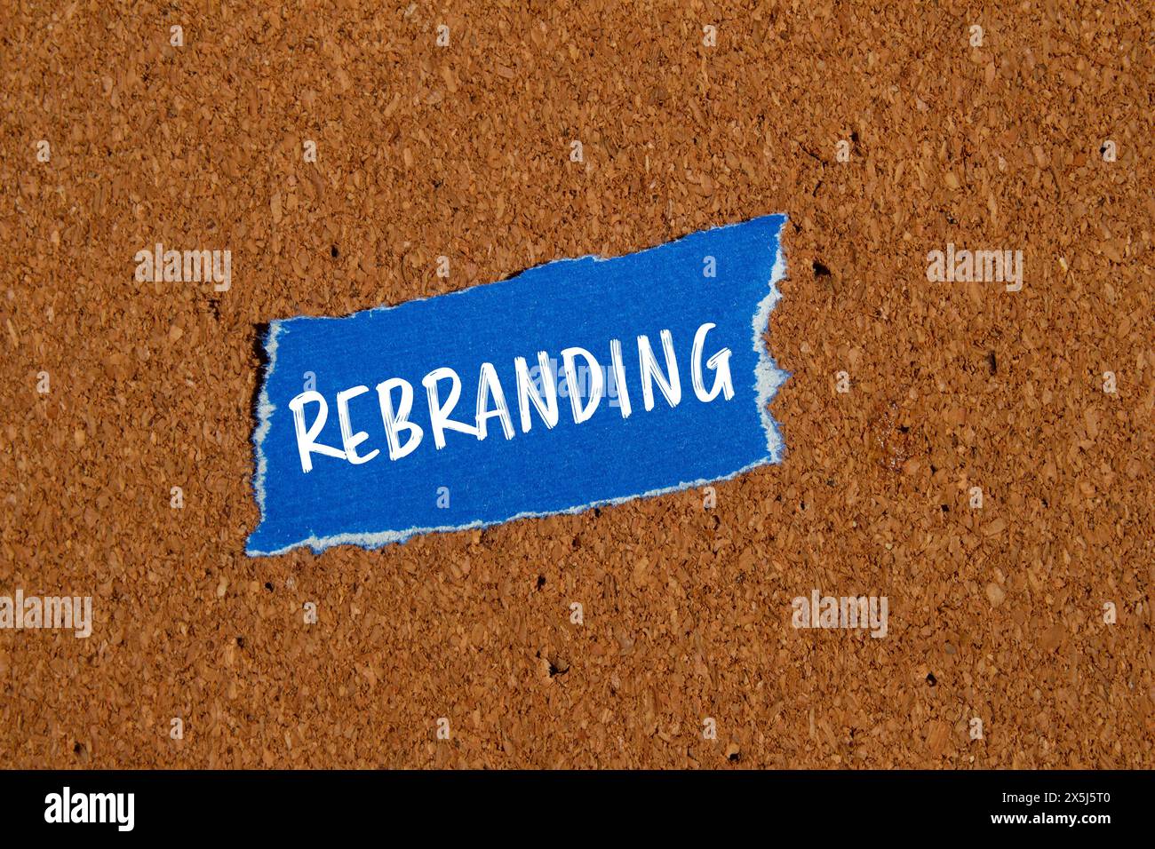 Rebranding word written on ripped blue paper piece with brown ...